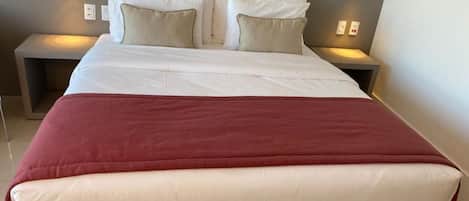 Quarto de hotel moderno com uma cama grande, duas mesas de cabeceira e uma cabeceira.