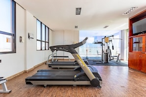 Academia com esteiras, bicicleta ergométrica e aparelho de musculação.