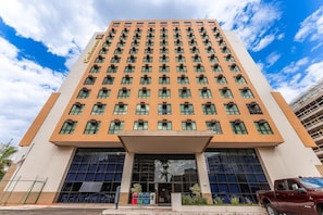 Hotel com vários andares e design moderno, com uma entrada imponente, grandes janelas e telhado plano.