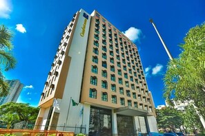 Hotel com vários andares, entrada destacada e uma bandeira.