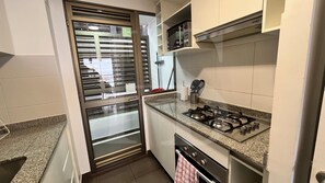 Cozinha compacta com fogão a gás, micro-ondas e forno embutido.