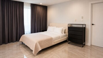 Quarto moderno com cama, mesa de cabeceira e porta.