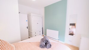 Quarto com cama, guarda-roupa, radiador e espelho refletindo uma cama.
