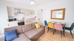 Apartamento moderno com cozinha compacta, área de jantar e sala de estar com sofá.