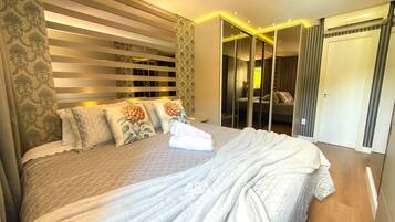 Um quarto com cama, mesas de cabeceira, espelho e guarda-roupa.