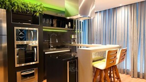 Cozinha moderna com eletrodomésticos embutidos, área de bar e vista para o exterior.