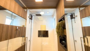 Interior moderno com divisórias de vidro, painéis de madeira e televisão na parede.