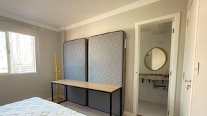 Quarto com cama, mesa de cabeceira, guarda-roupa e janela.