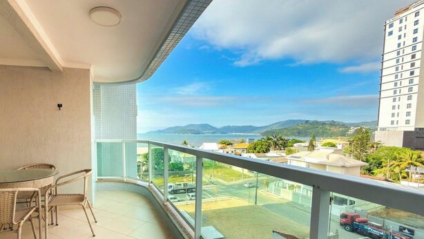Varanda com mesa e cadeiras, vista para um horizonte urbano com edifícios e uma cordilheira ao longe.