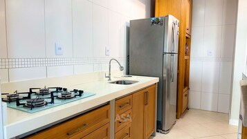 Cozinha moderna com fogão a gás, geladeira de aço inoxidável e armários de madeira.