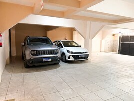 Dois carros estacionados em um edifício com piso de azulejos e um extintor de incêndio na parede.