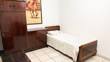 Quarto com cama, guarda-roupa de madeira e quadro na parede.