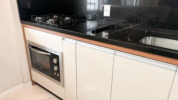 Uma cozinha com fogão, forno e escorredor de louça.