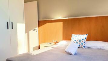 Quarto de hotel com cama, mesa de cabeceira, cabeceira de madeira e guarda-roupa.