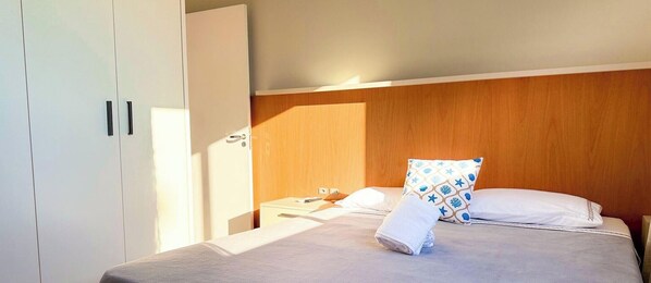 Quarto de hotel com cama, mesa de cabeceira, cabeceira de madeira e guarda-roupa.