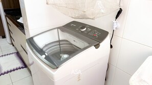Máquina de lavar de abertura frontal com painel de controle, cabo de alimentação e capa protetora de malha.