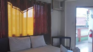 Quarto de hotel com cama, cortinas, mesa de cabeceira com toalhas e aparelho de ar condicionado.
