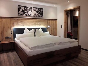 Quarto com uma cama grande, cabeceira de madeira e uma pintura sobre a cama.