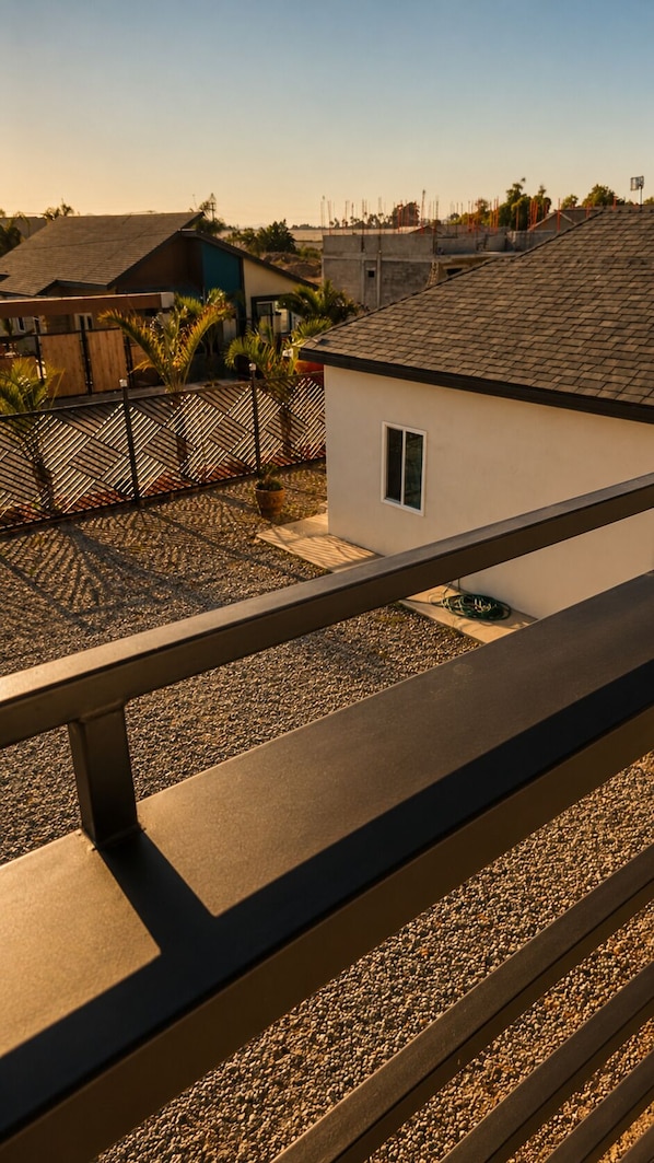 Um edifício residencial com telhado inclinado, uma pequena janela e área pavimentada com pedrisco.