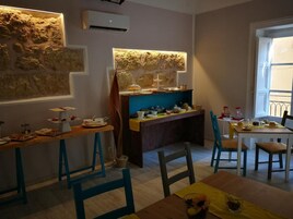 Espaço de refeições com parede de pedra, balcão de buffet e mesa com cadeiras.