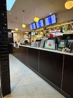Uma área de bar com balcão, cardápios e seleção de garrafas.