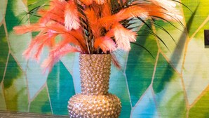 Um vaso decorativo com penas de pavão e folhas de palmeira sobre uma superfície de mármore.