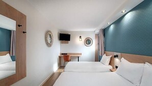Quarto de hotel com duas camas, uma escrivaninha, televisão e um espelho.