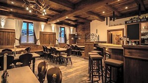 Interior rústico com vigas de madeira, área de bar e espaço para refeições.