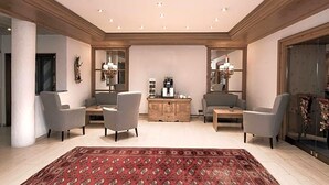 Um quarto amplo com um tapete vermelho estampado, um armário de madeira e duas poltronas.