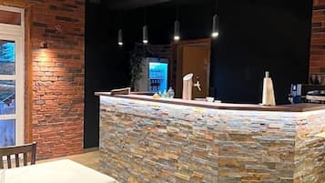Restaurante com balcão de pedra e teto de madeira.