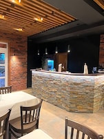 Restaurante com balcão de pedra e teto de madeira.