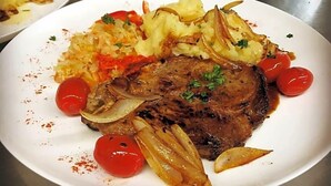Prato com bife, batatas e tomates cereja.