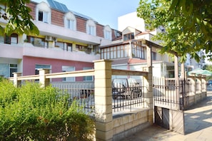 Um edifício residencial com várias varandas, entrada com portão e caminho pavimentado.