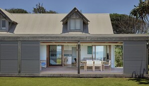 Uma casa moderna com varanda coberta, amplas portas de vidro deslizantes e área de jantar.