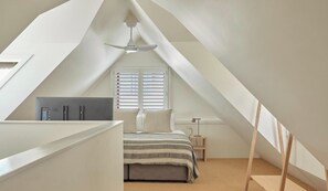 Quarto com cama, escrivaninha, cadeira, janela com persianas e ventilador de teto.