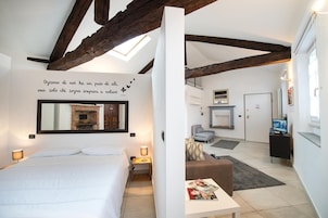 Quarto de hotel com cama, espelho, lareira e televisão.