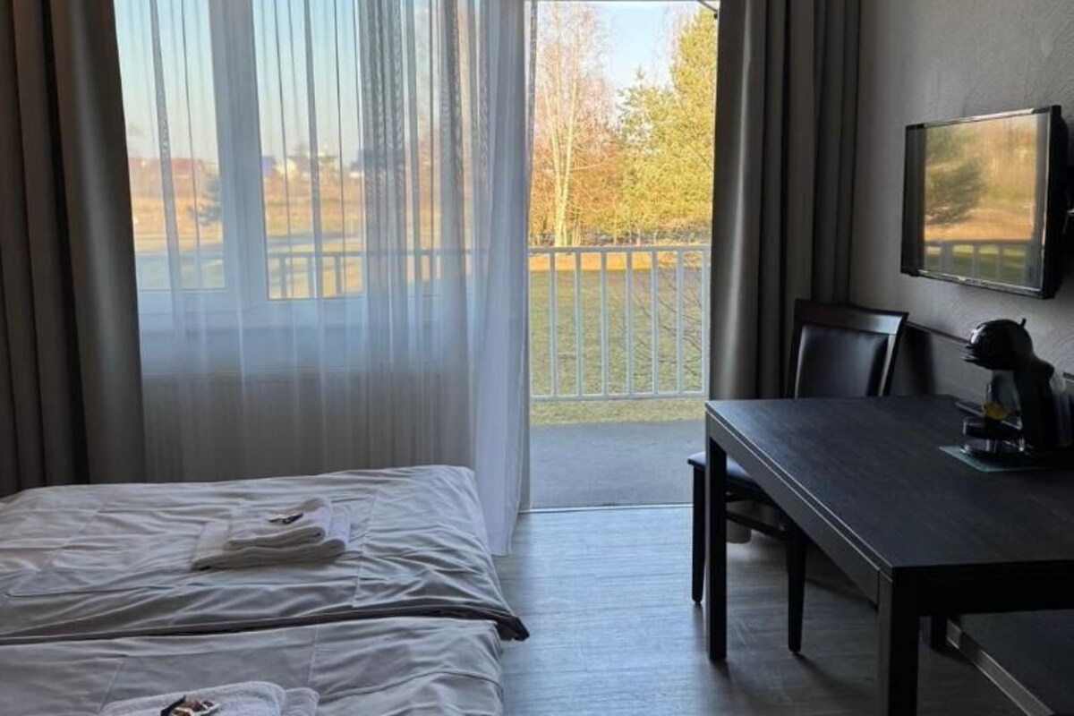 Quarto de hotel com cama, mesa e televisão.