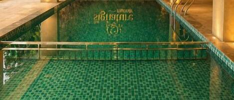 Piscina interna com piso ladrilhado e um logotipo na parede.