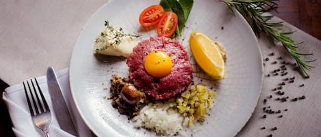 Um prato com carne crua, um ovo cozido e alguns vegetais.