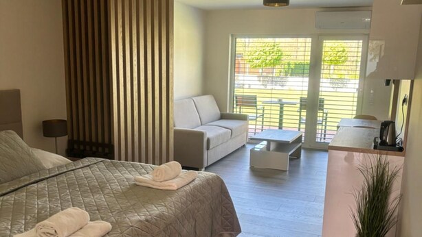 Quarto de hotel moderno com uma cama grande, um sofá, uma mesinha e um vaso de planta.