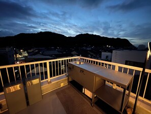 Terraço no telhado com cozinha, pia e vista para a cidade ao entardecer.