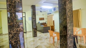 Quarto com piso de mármore, área de jantar com cadeiras de plástico, bancada de cozinha e ventilador de teto.