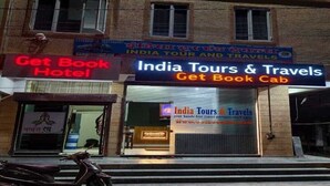 Um edifício com placas de 'India Tours & Travels' e 'Get Book Cab'.