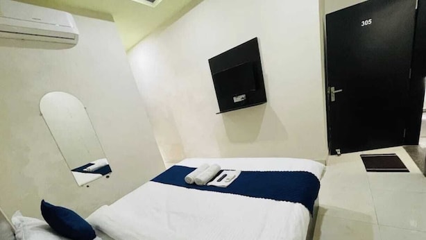 Quarto de hotel com cama, mesa de cabeceira, espelho, porta e ar condicionado.