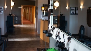 Um interior moderno com um corredor longo que leva a uma porta, um revestimento de couro de vaca refletivo e um console preto com uma planta verde.