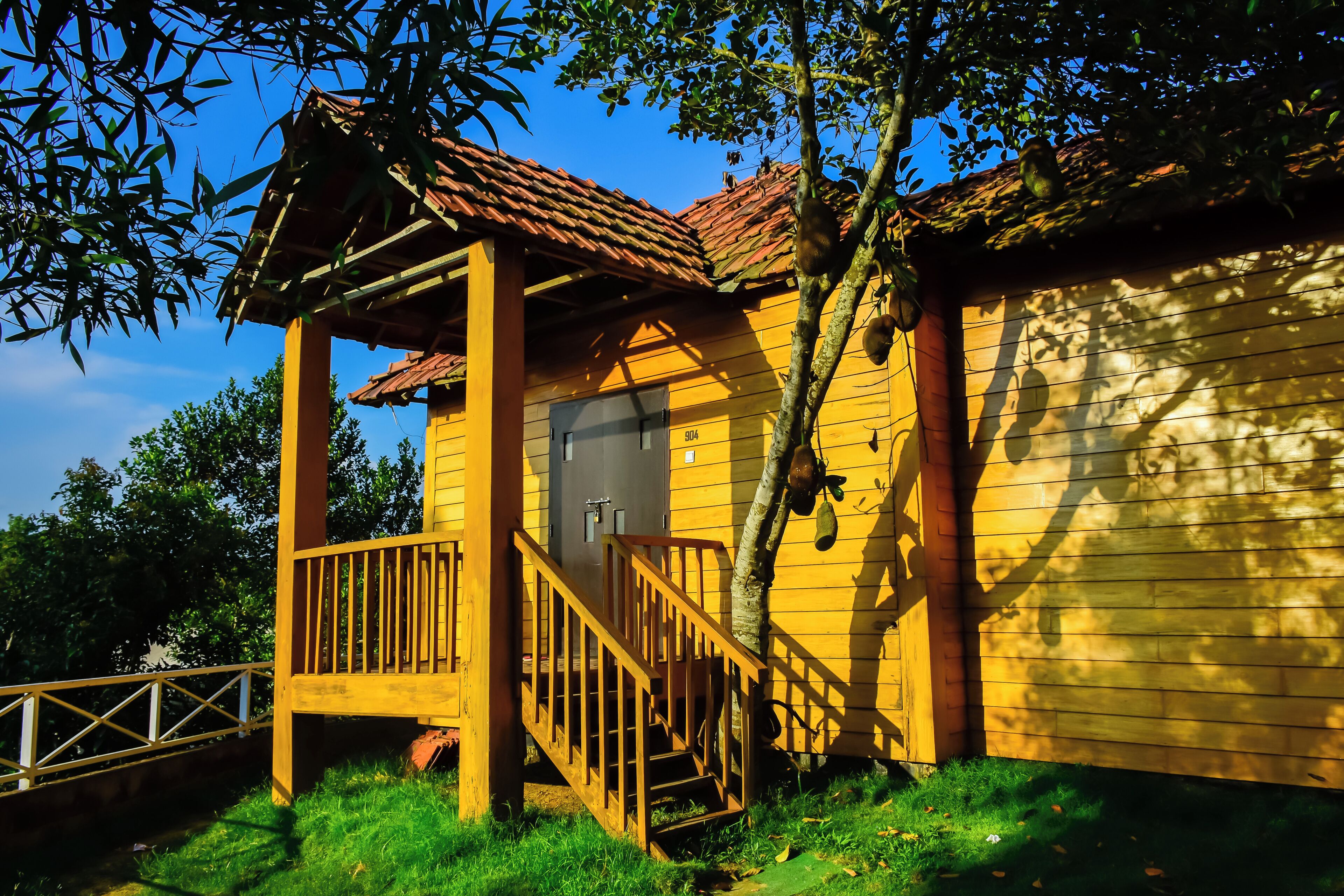 Uma cabana de madeira com varanda, escadas e uma porta.
