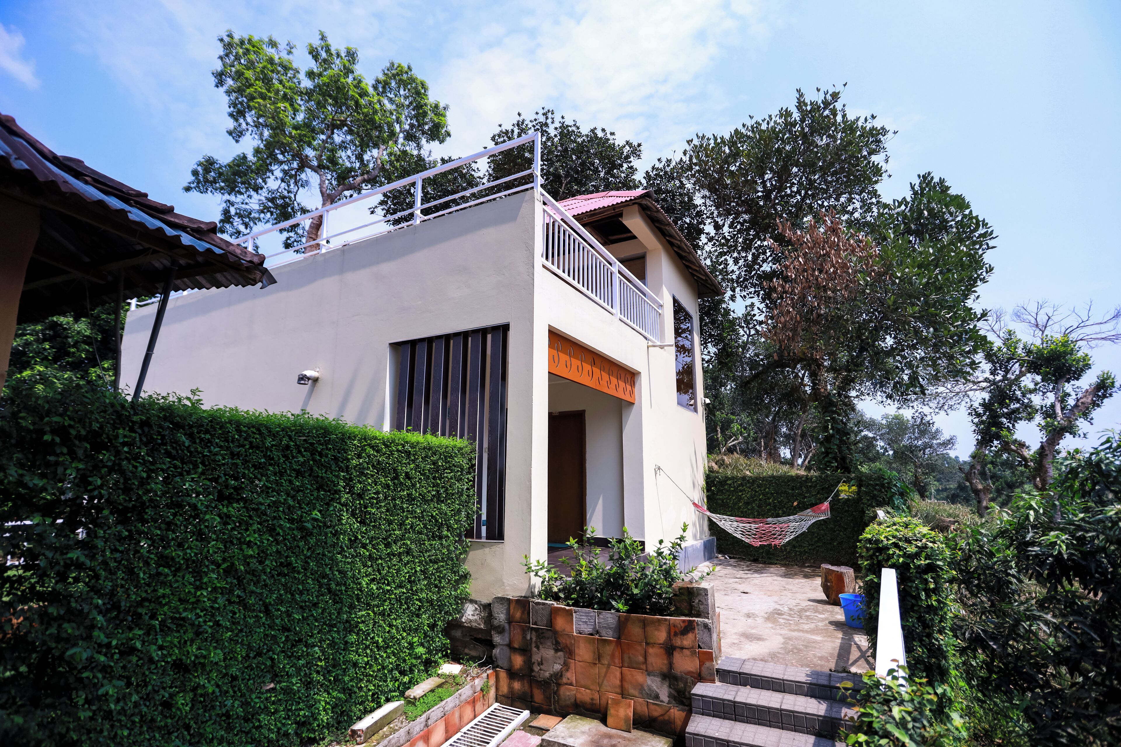 Uma casa moderna de dois andares com varanda, um pequeno jardim e entrada pavimentada.