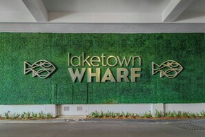 Um letreiro com o texto 'laketown WHARF' e dois símbolos de peixe em uma parede verde.