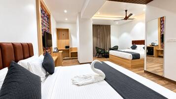 Quarto de hotel com uma cama grande, escrivaninha, cadeira, espelho e ventoinha no teto.
