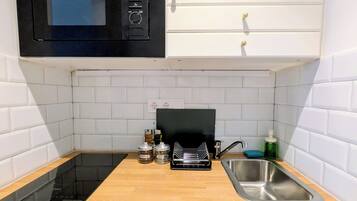 Uma cozinha compacta equipada com micro-ondas, pia e lava-louças.
